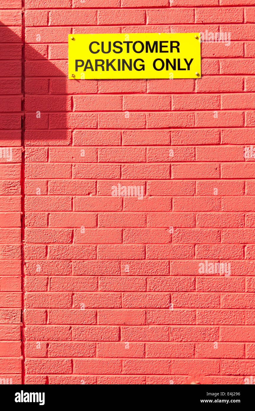 Yellow sign on a red wall saying "Customer Parking Only Stock Photo - Alamy
