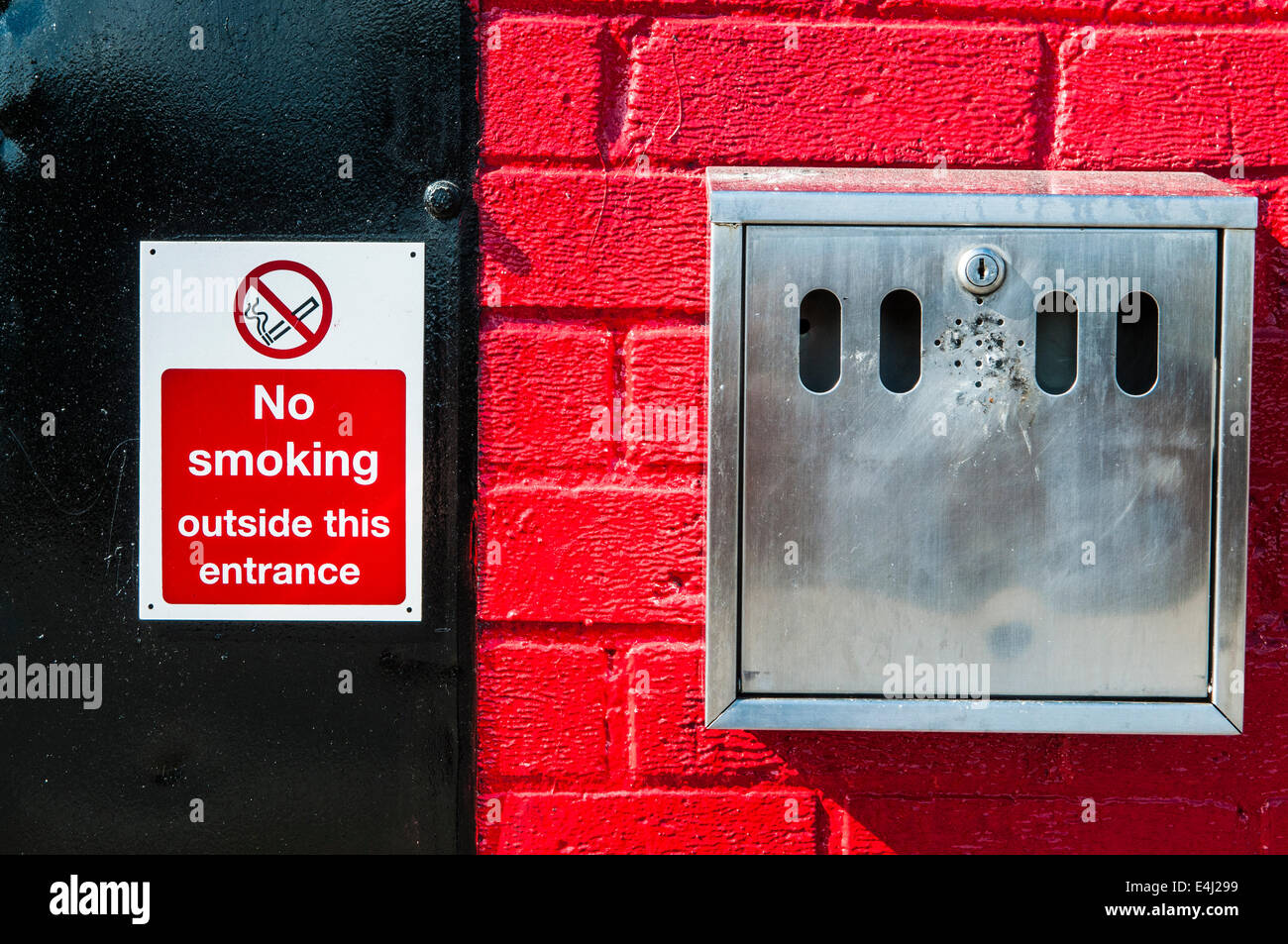 Sign warning people not to smoke outside an entrance, but making it ...