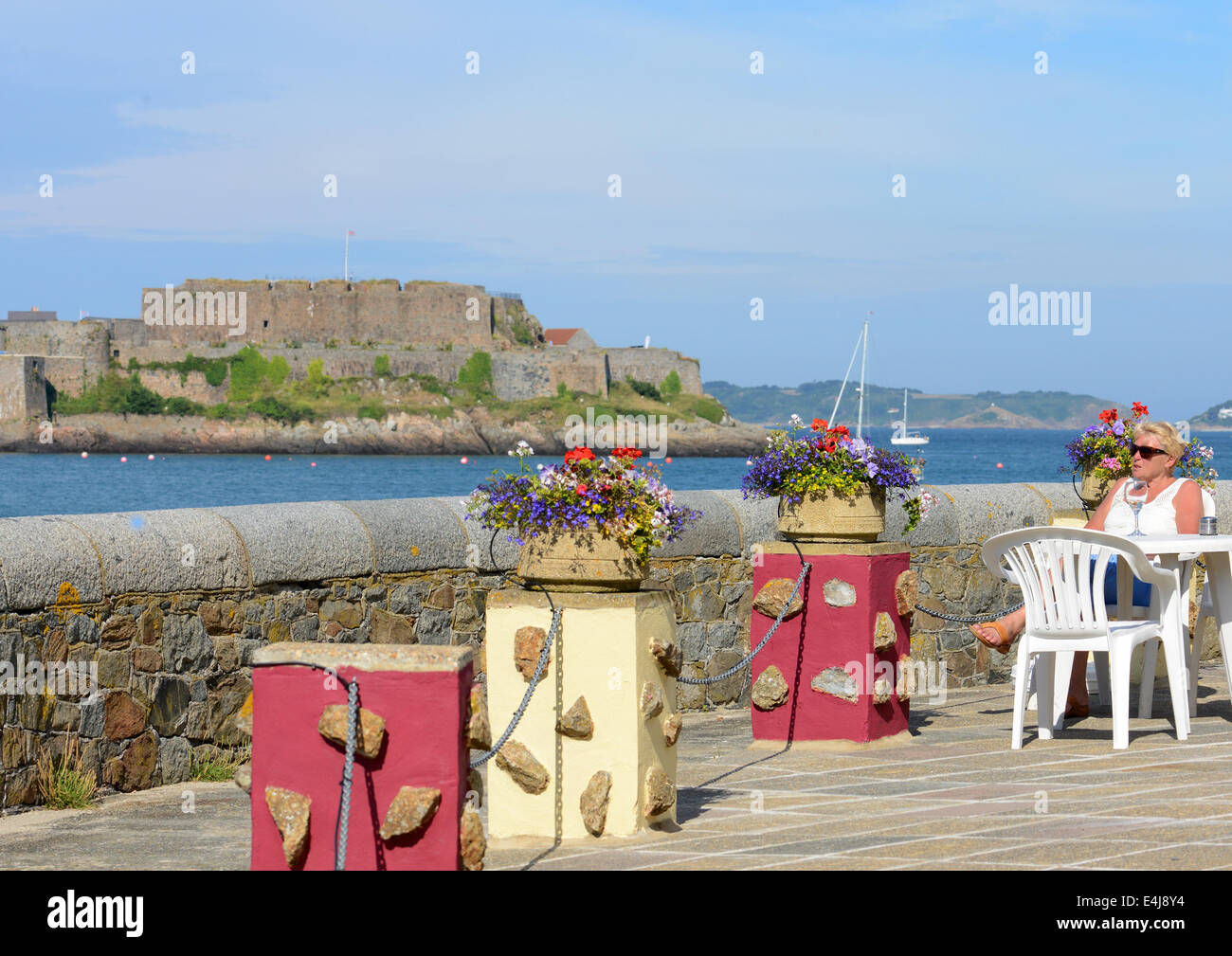 A woman enjoys a glass of wine while looking out over Castle Cornet and ...