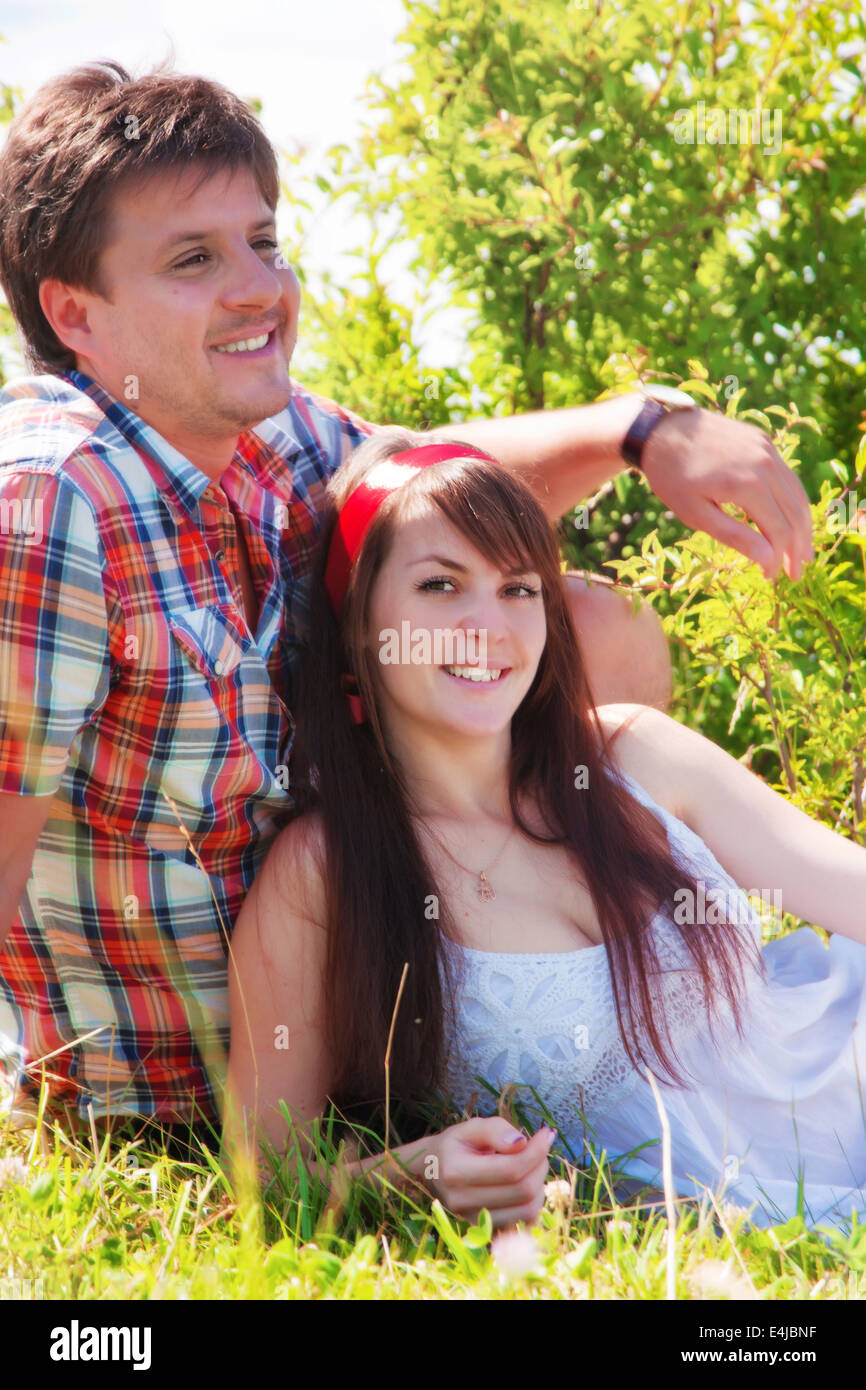 Smiling couple resting near a tree Stock Photo - Alamy