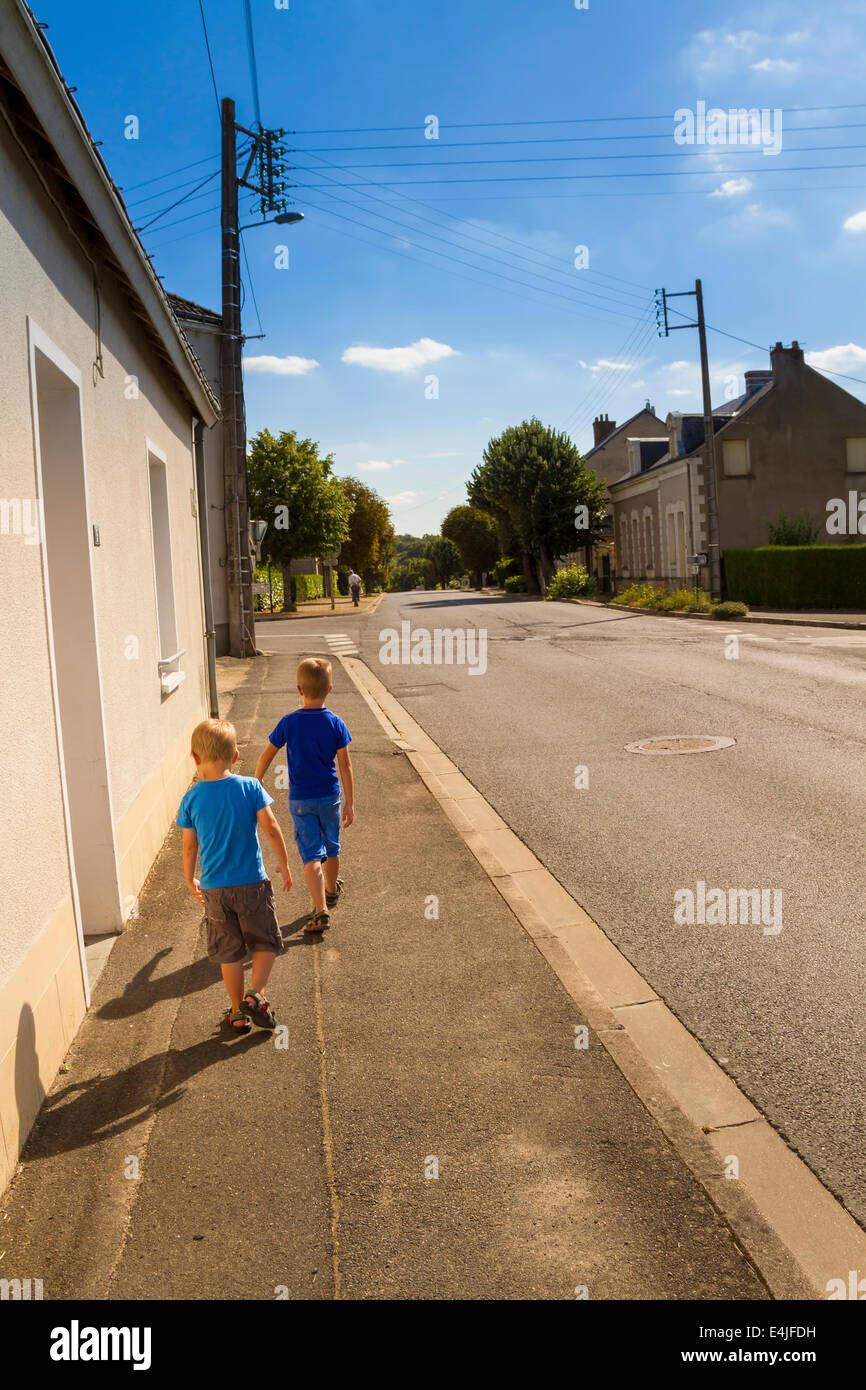 Two young boys walking on the sidewalk Stock Photo - Alamy