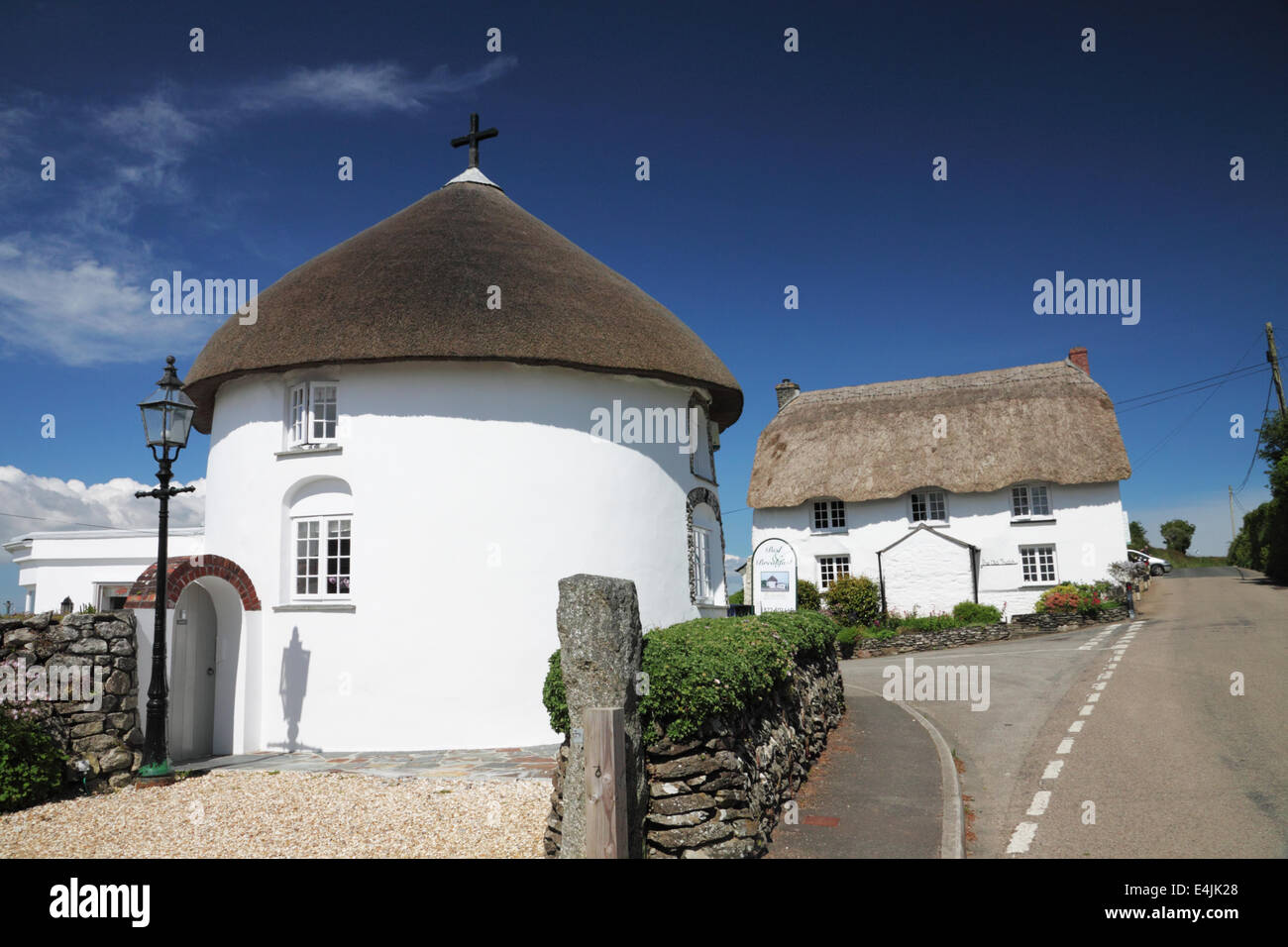 A circular thatched cottage and a thatched cottage with eyebrows behind ...