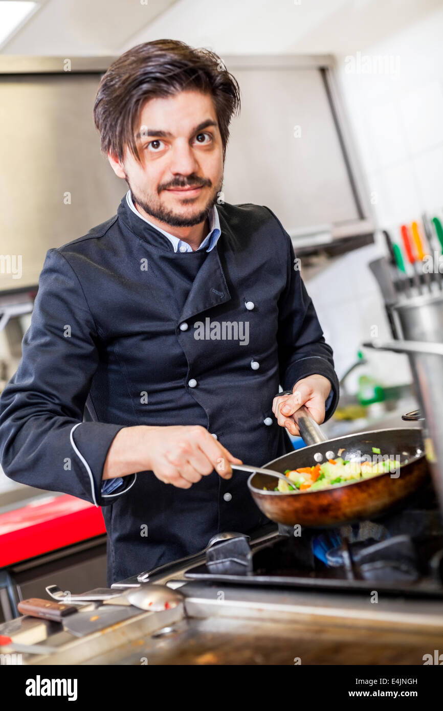 Professional chef in a commercial kitchen cooking a vegetable stir fry ...