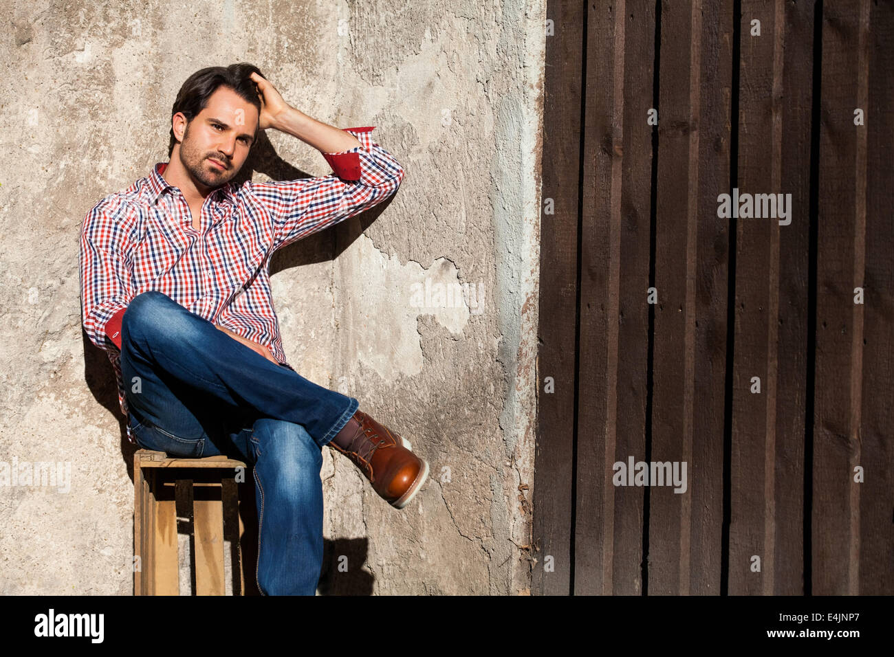 Smiling male model sitting on wooden crate with legs crossed Stock ...