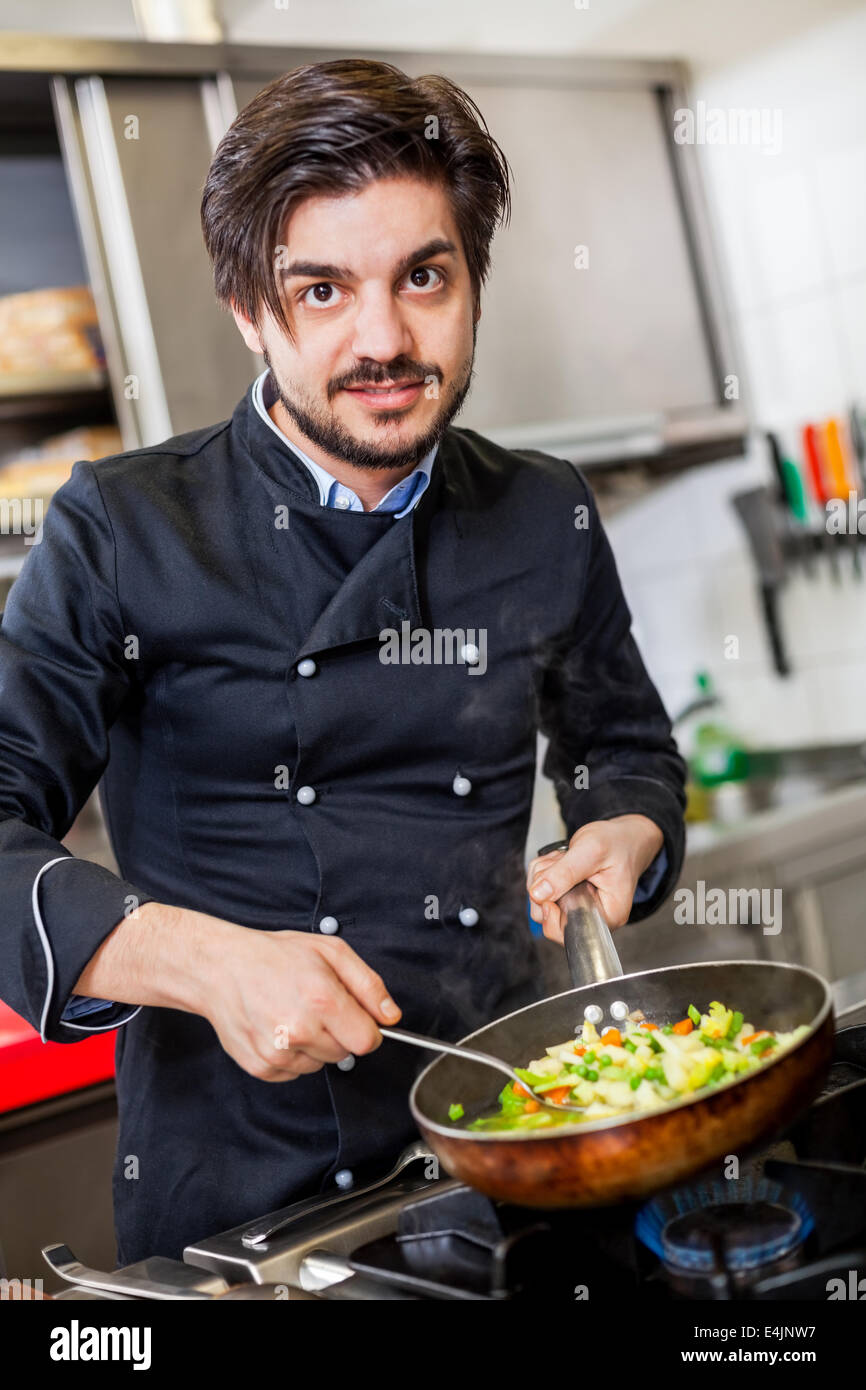Professional chef in a commercial kitchen cooking a vegetable stir fry ...