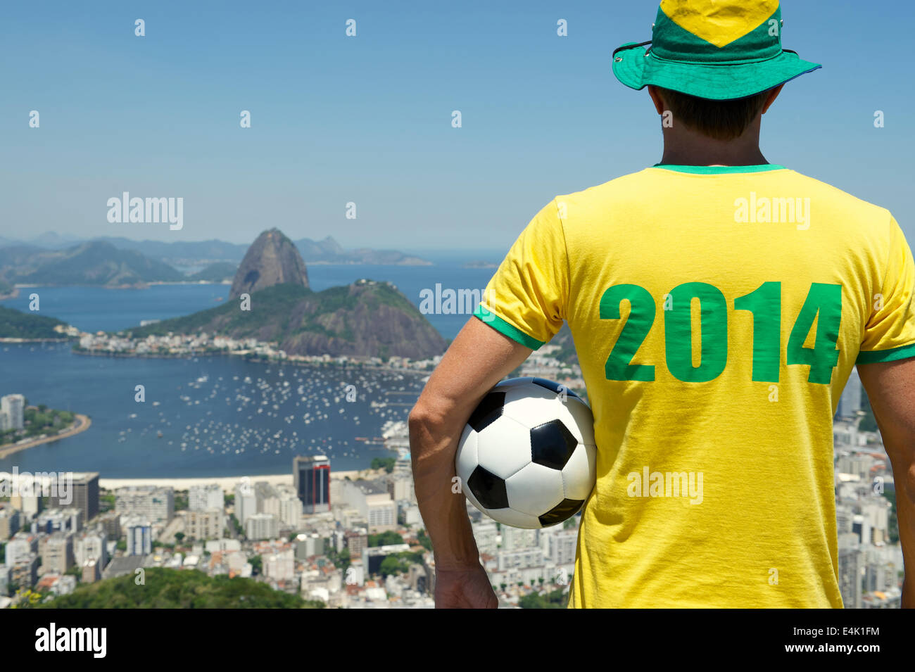 Man in Brazil hat and 2014 shirt standing with football bright sunny ...