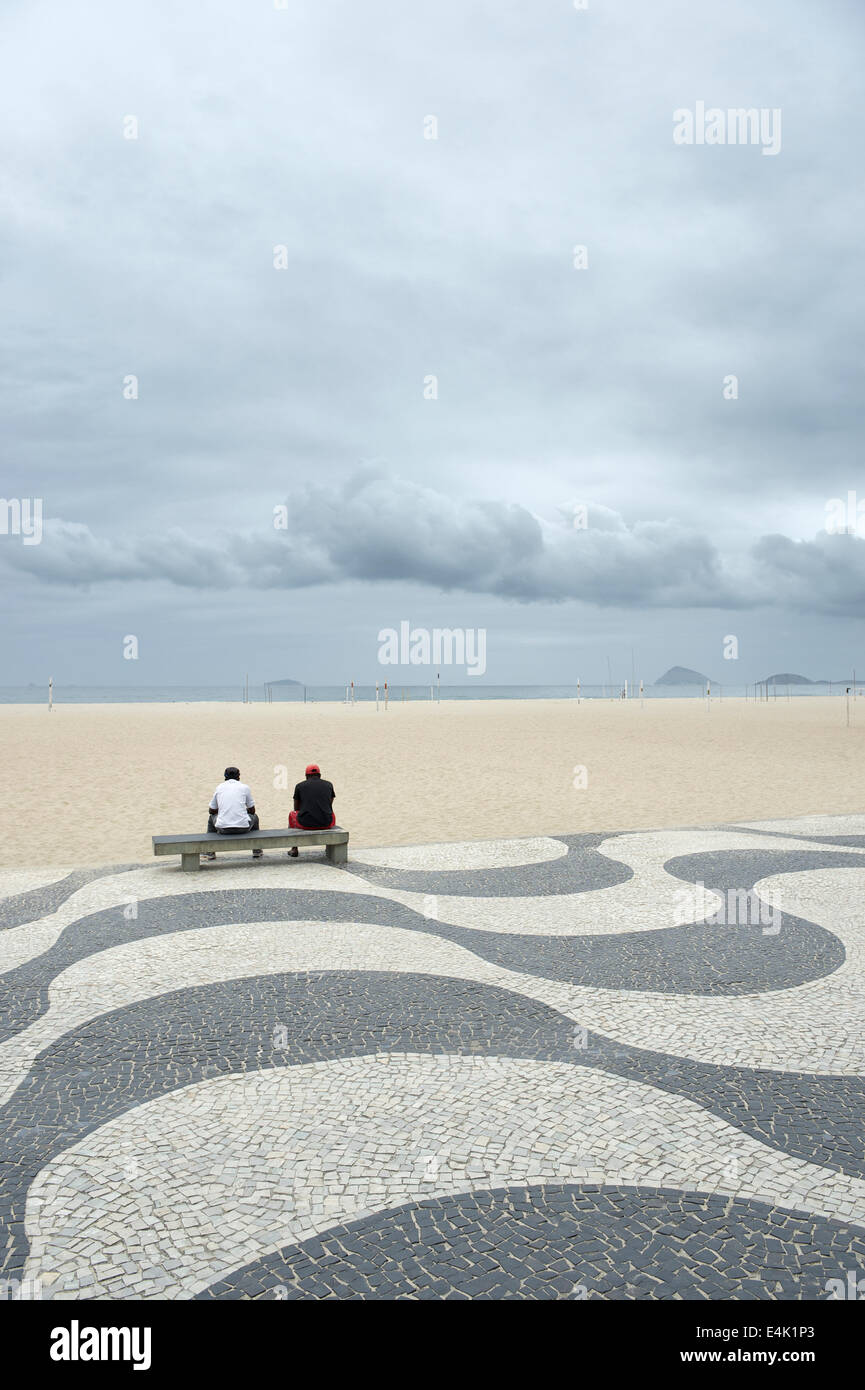 Figures sit on bench at iconic sidewalk tile pattern before empty view ...