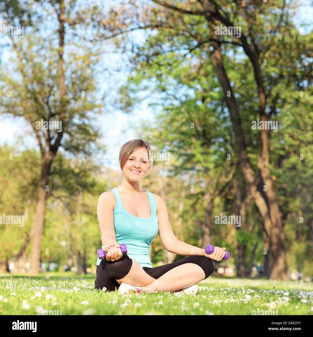 Young girl exercising with dumbbells in park seated on grass Stock ...