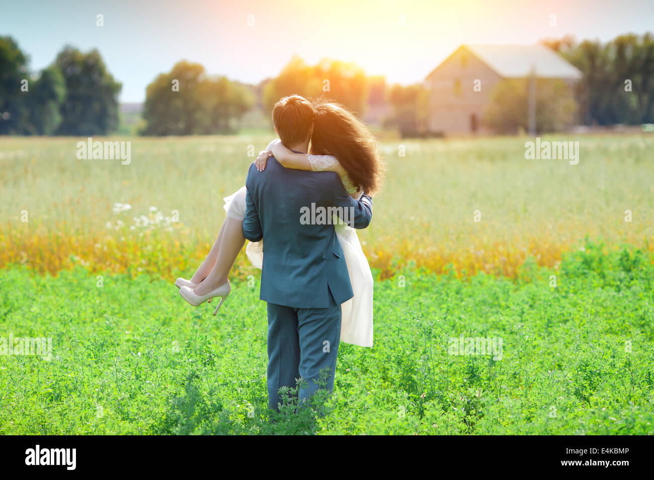 Groom carrying his bride in the clover field Stock Photo - Alamy