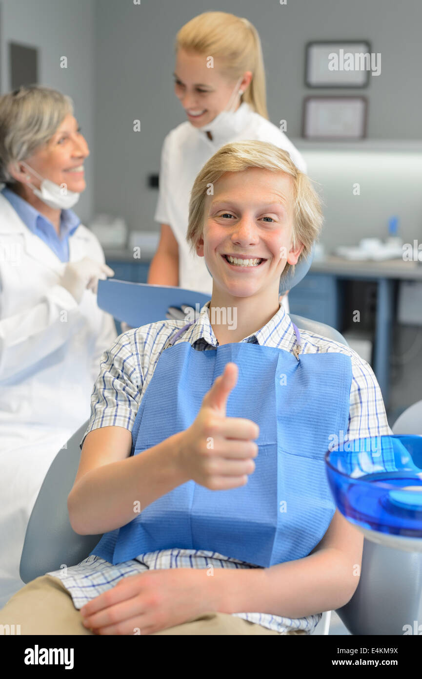 Teenager patient thumbup at dental surgery dentist and nurse background ...