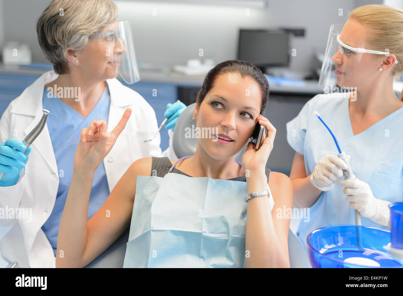 Busy businesswoman at dental surgery calling on phone dentists waiting ...