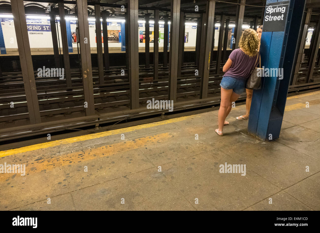 Two young women in shorts wait for a train on the platform of the ...