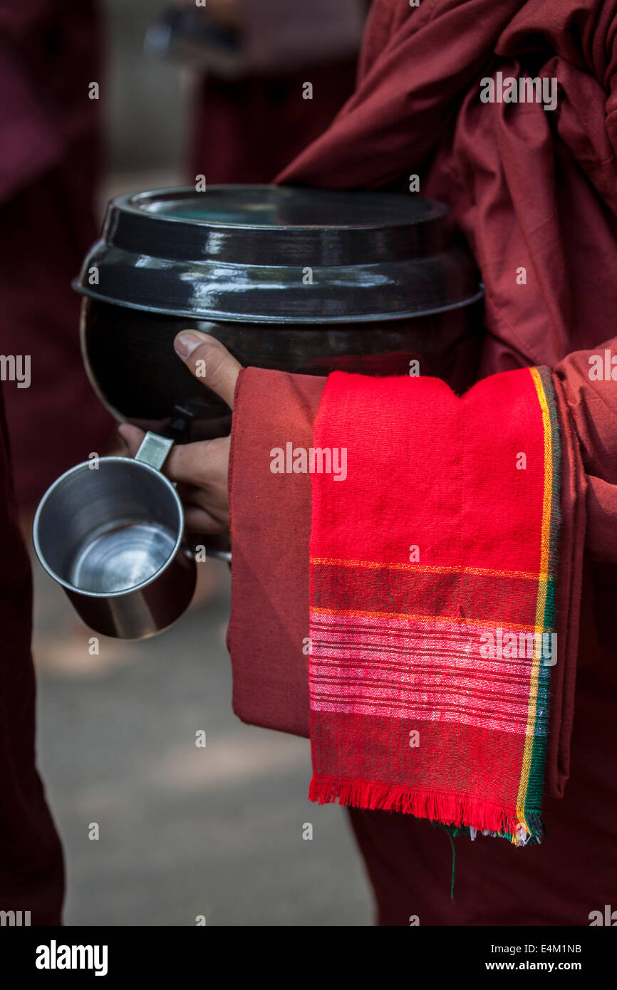 A food bowl and water cup are held by a Buddhist monk who is in a ...