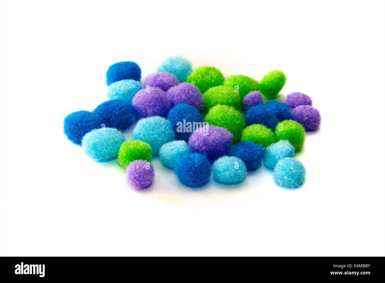 A collection of colorful craft pompoms shot over white of various ...
