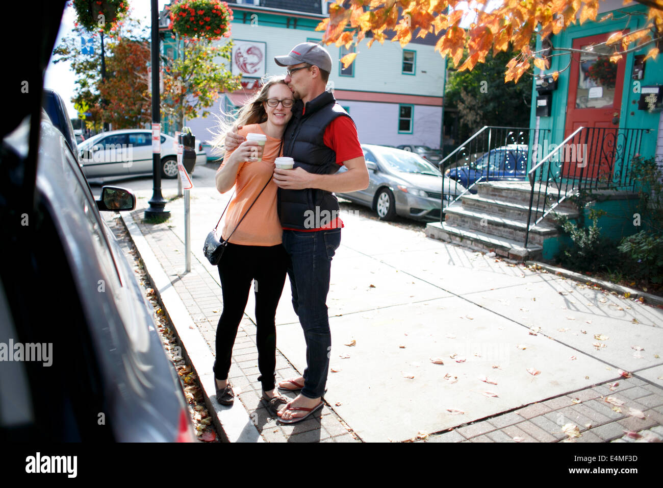 Couple Hugging and Holding Coffee Cups on Sidewalk Stock Photo - Alamy