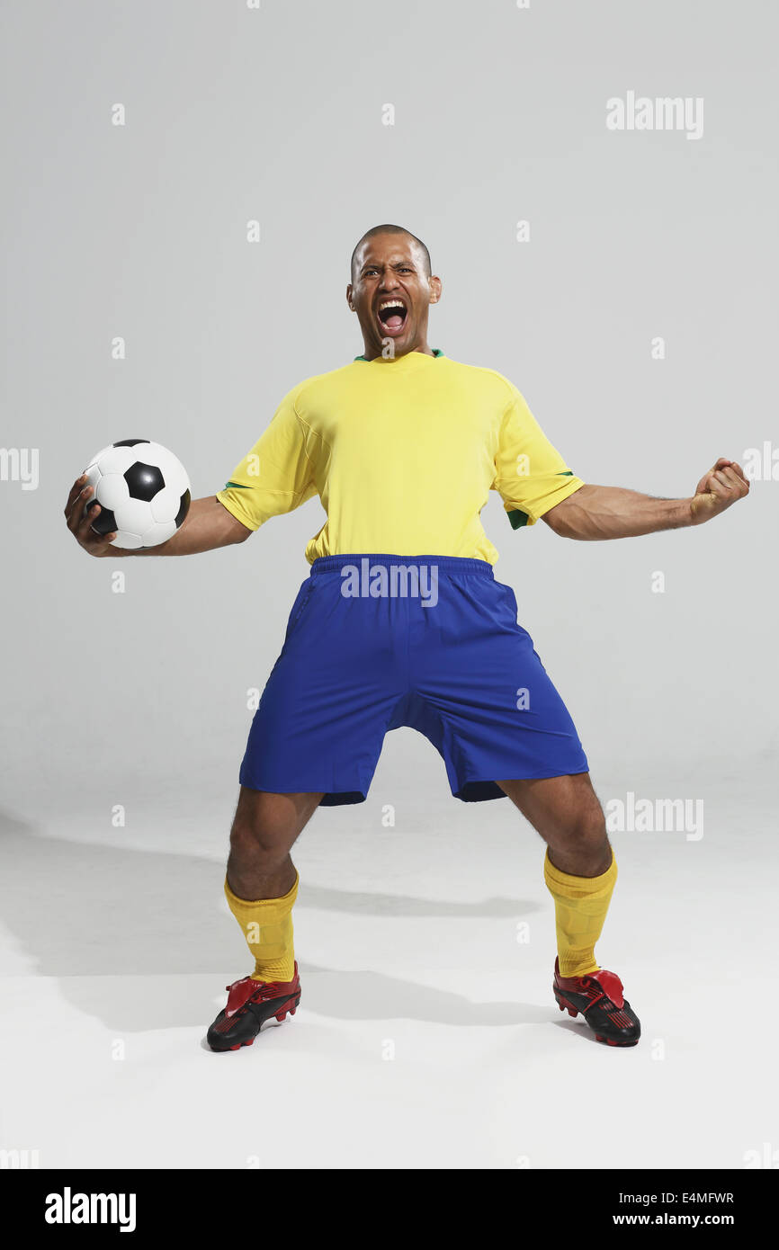 Football player in a yellow and blue uniform standing against white ...