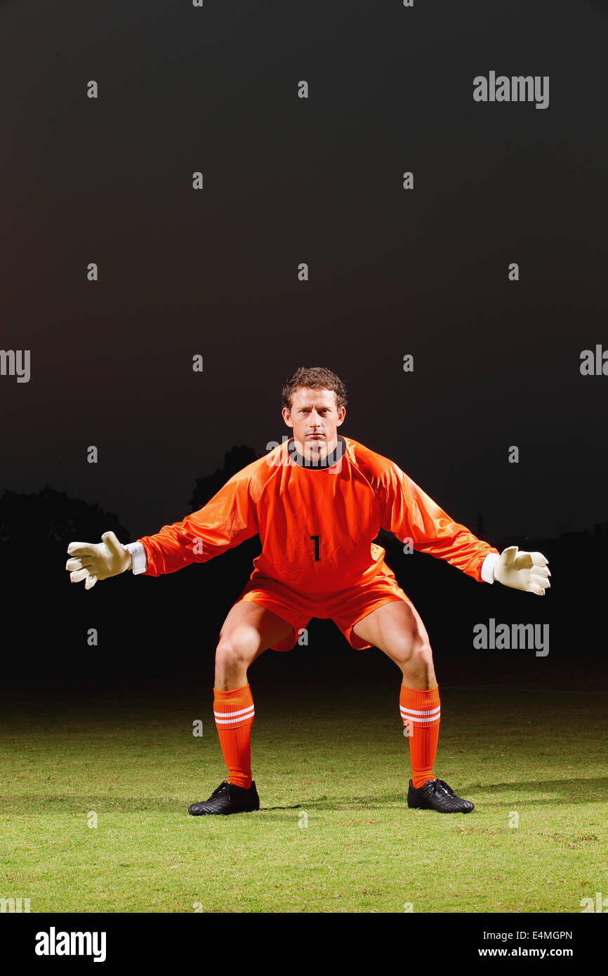 Goalkeeper in orange uniform standing in soccer field Stock Photo - Alamy