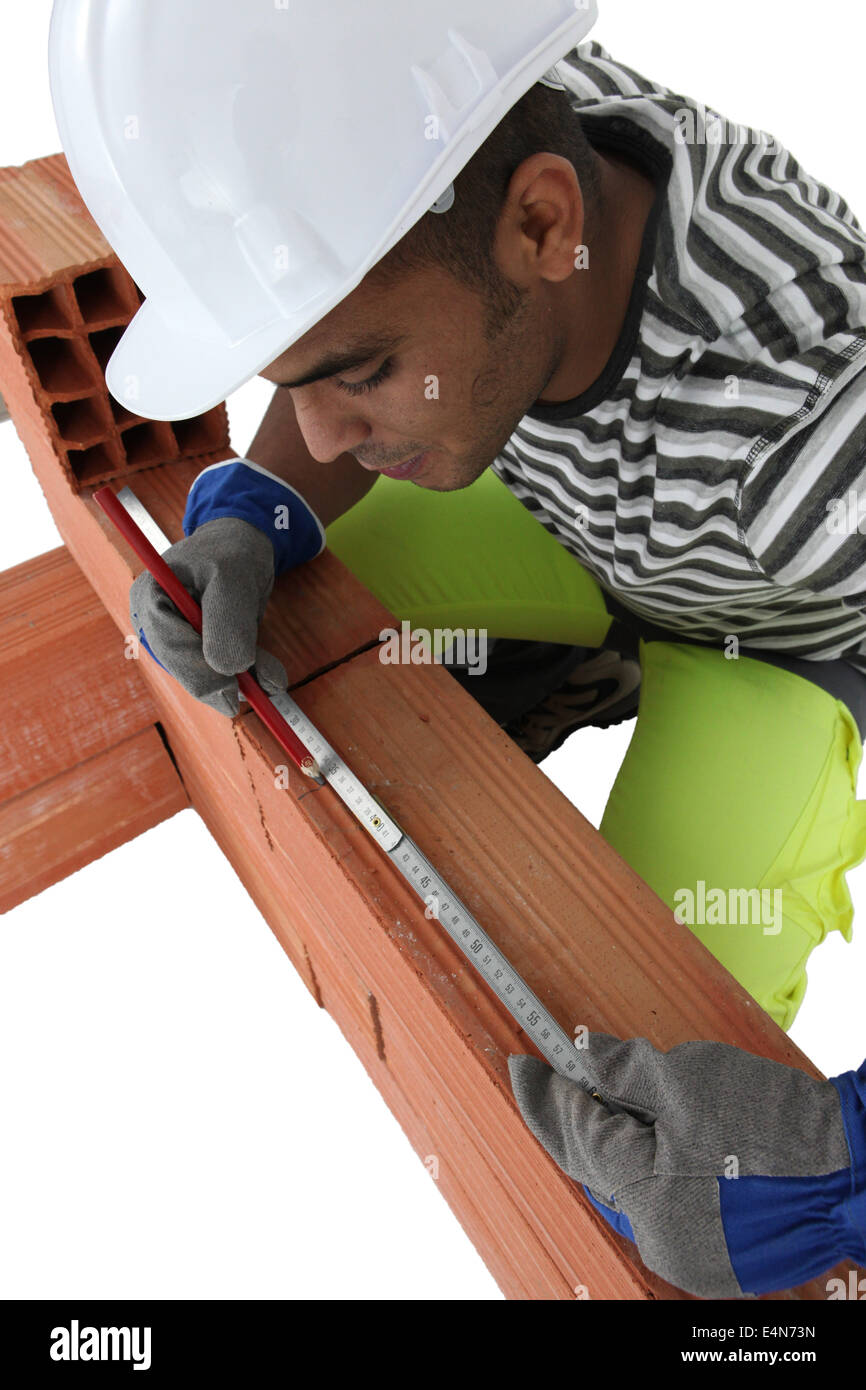 Mason measuring length of brick Stock Photo - Alamy