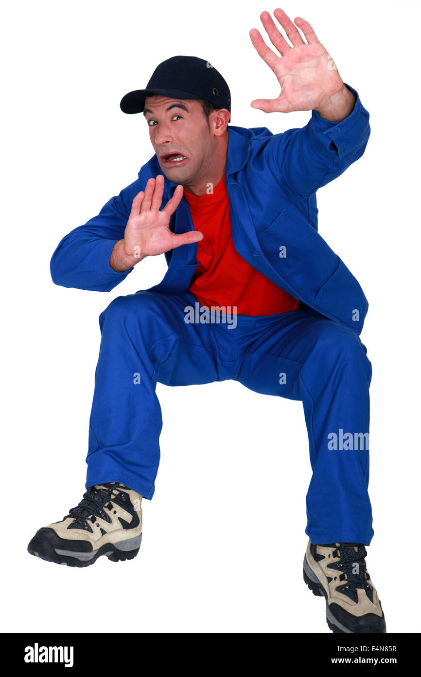 Scared plumber shielding face Stock Photo - Alamy