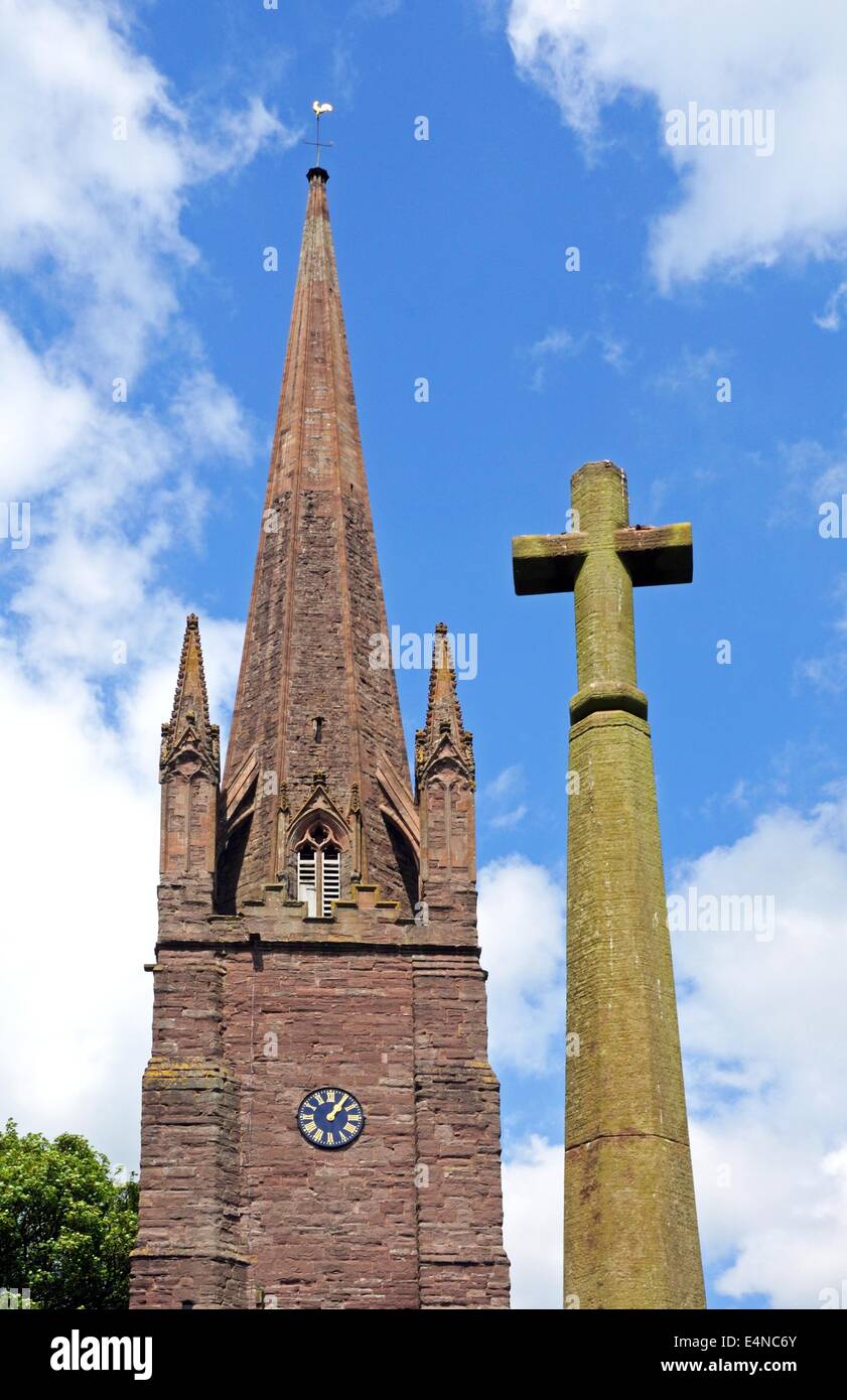 St Peter and St Paul church spire with a stone cross in the foreground ...