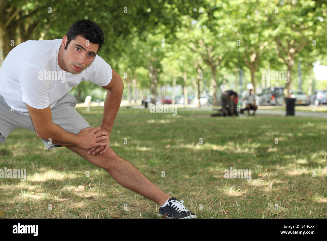 young man doing stretching exercises in park Stock Photo - Alamy