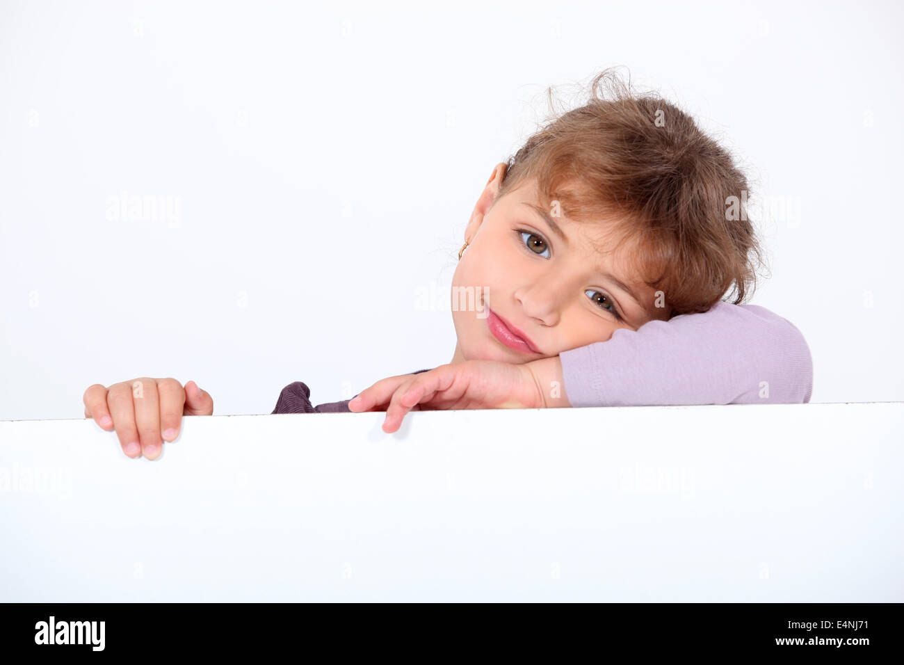Lovely little girl leaning on a white panel Stock Photo - Alamy