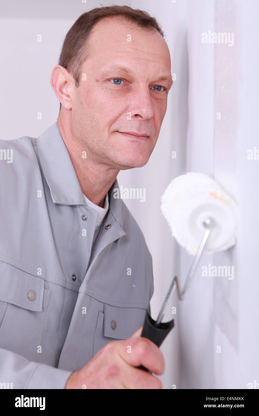 Decorator painting a room white Stock Photo - Alamy