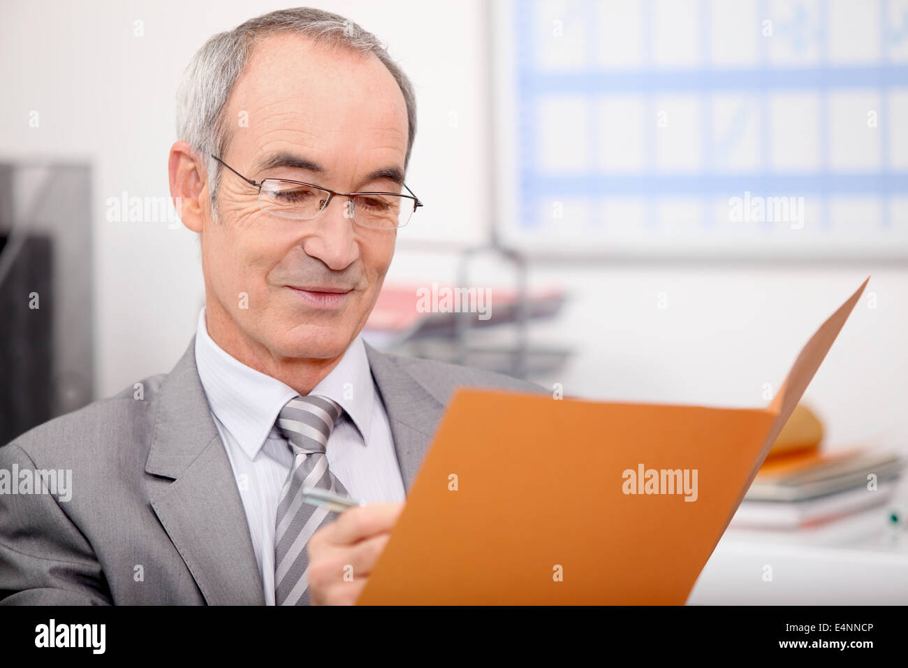 Older businessman writing in a file Stock Photo - Alamy