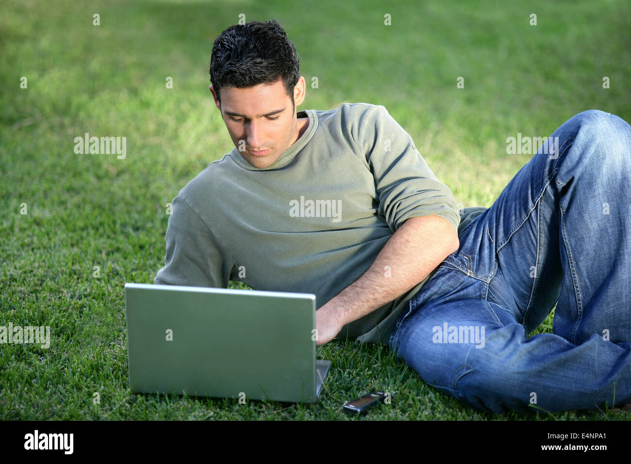 Man with laptop laying in field Stock Photo - Alamy