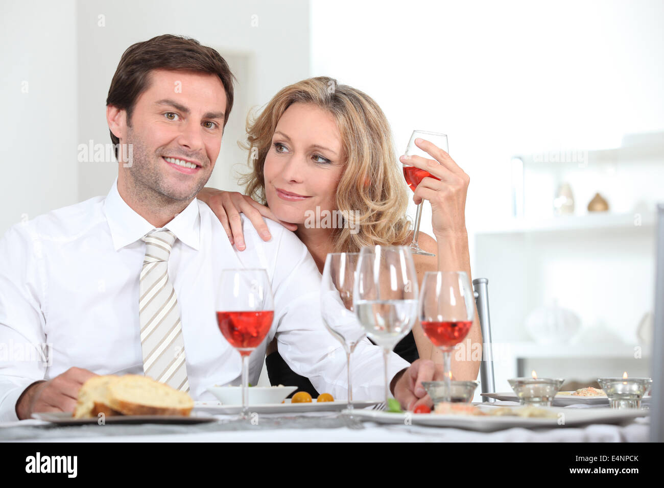 Couple sat at table with wine Stock Photo - Alamy
