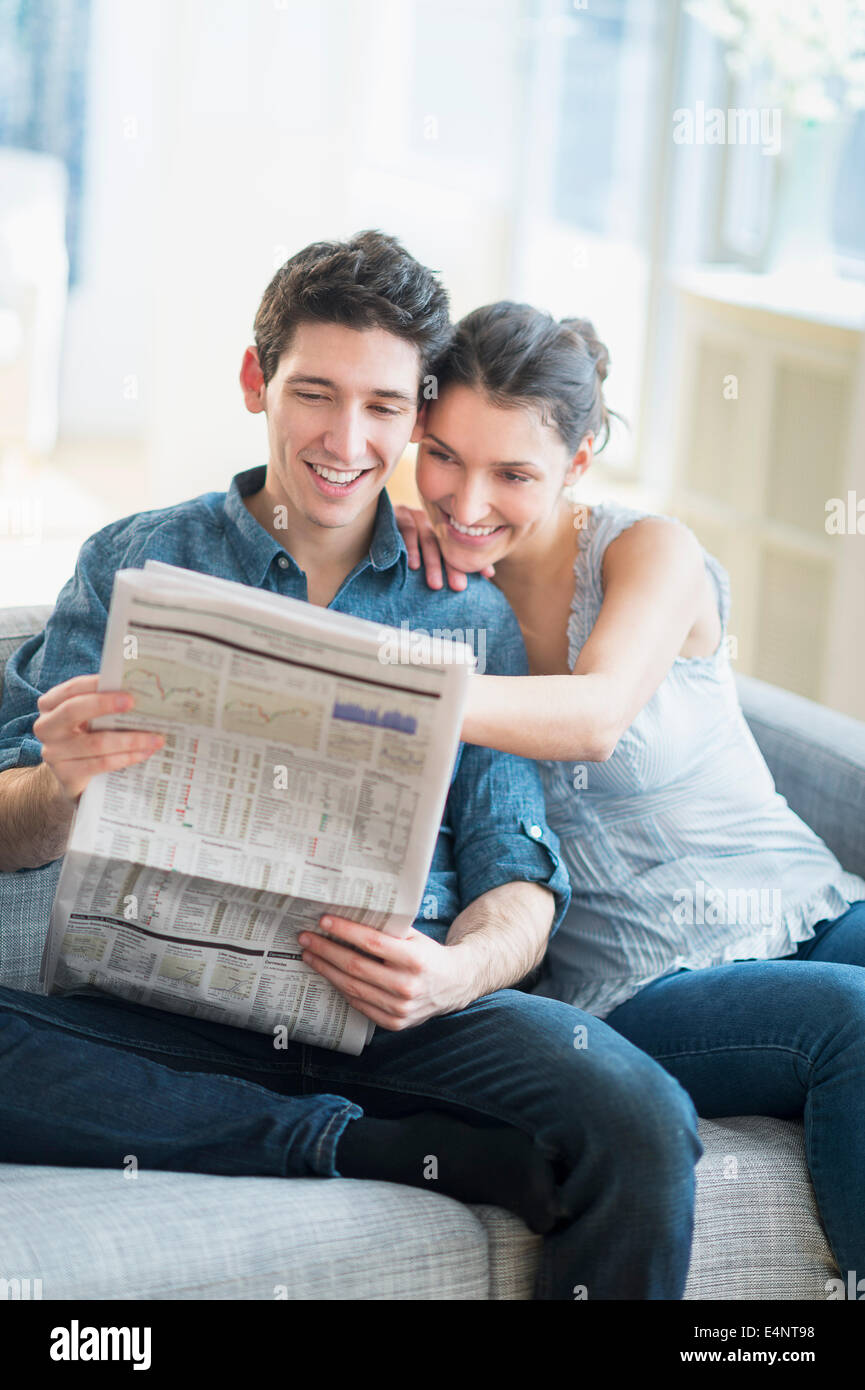 Couple reading newspaper on sofa Stock Photo - Alamy