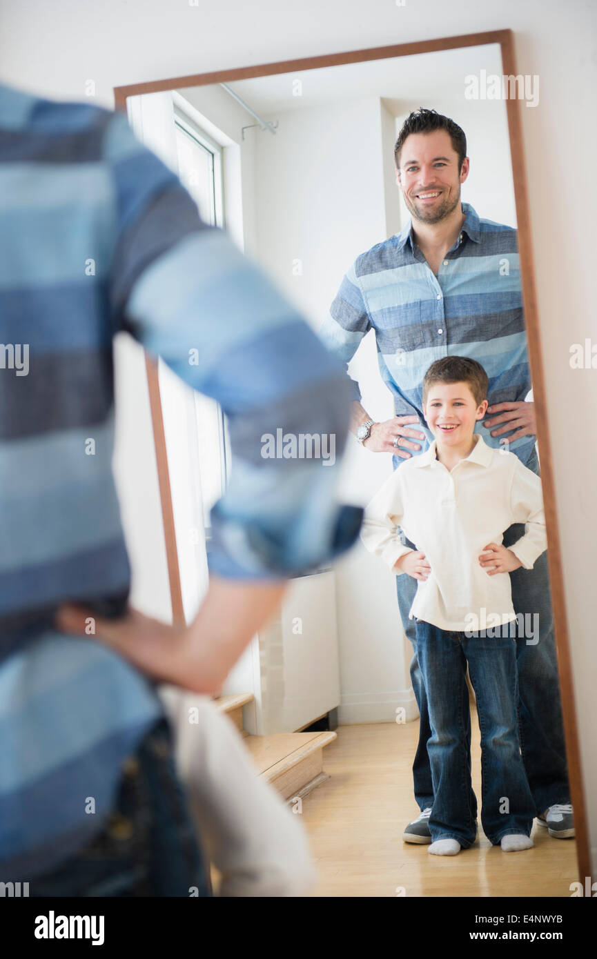 Father and son (8-9) looking at their reflection in mirror Stock Photo ...