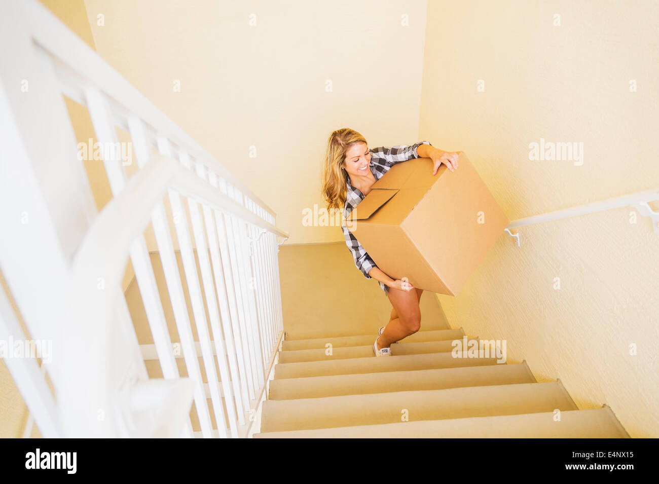 Young woman carrying box in her new house Stock Photo - Alamy