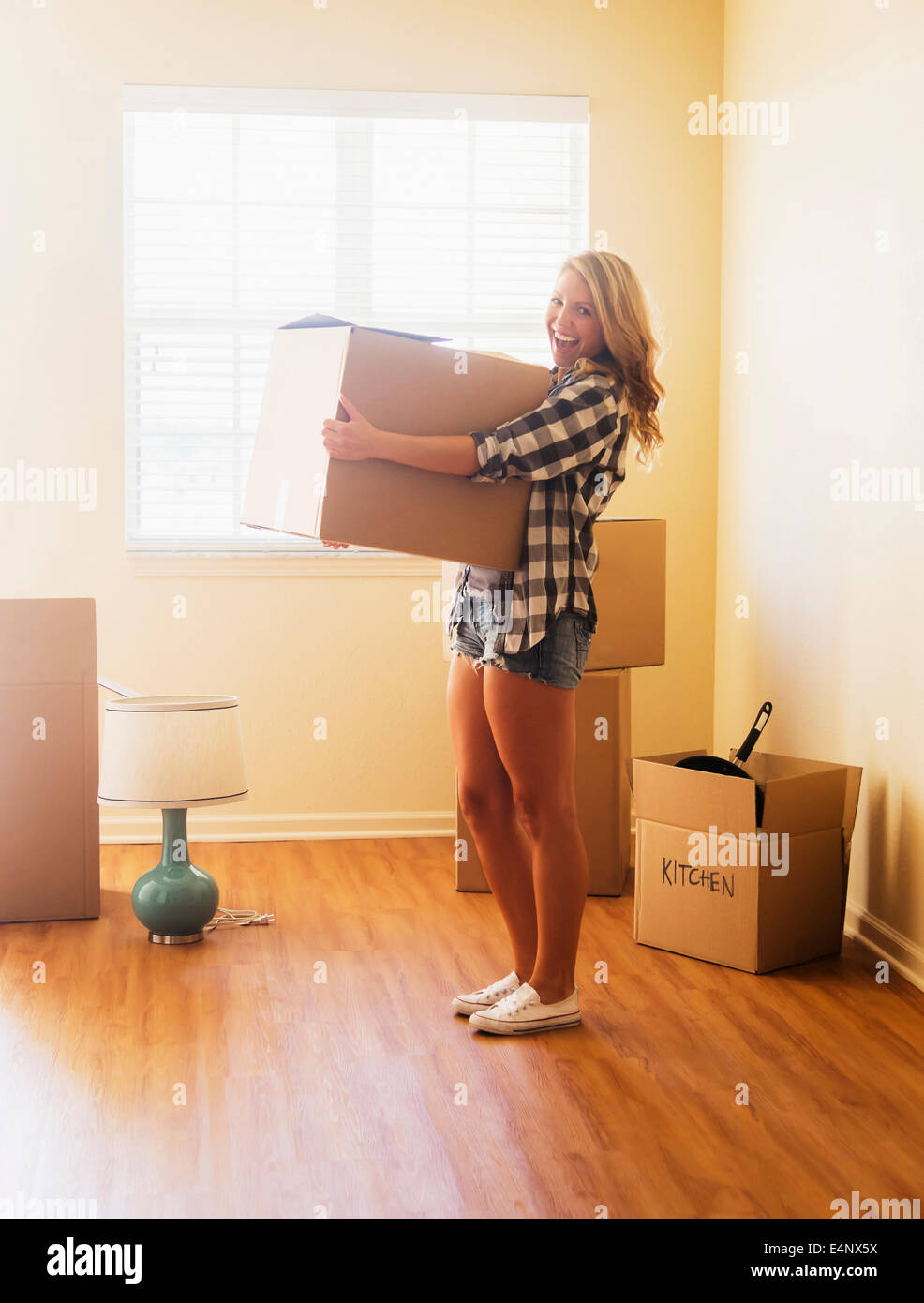 Young woman carrying box in her new house Stock Photo - Alamy