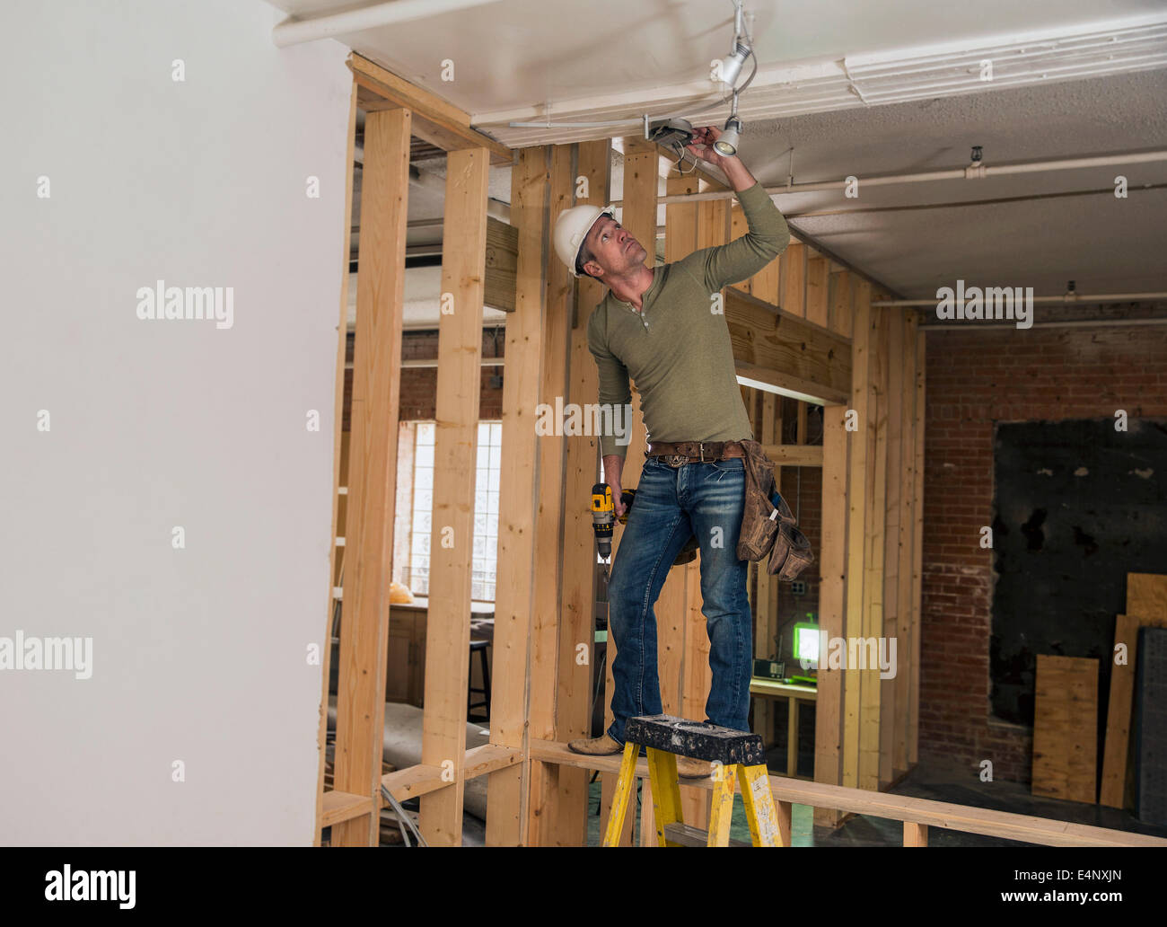 Construction worker drilling in ceiling inside new structure Stock ...