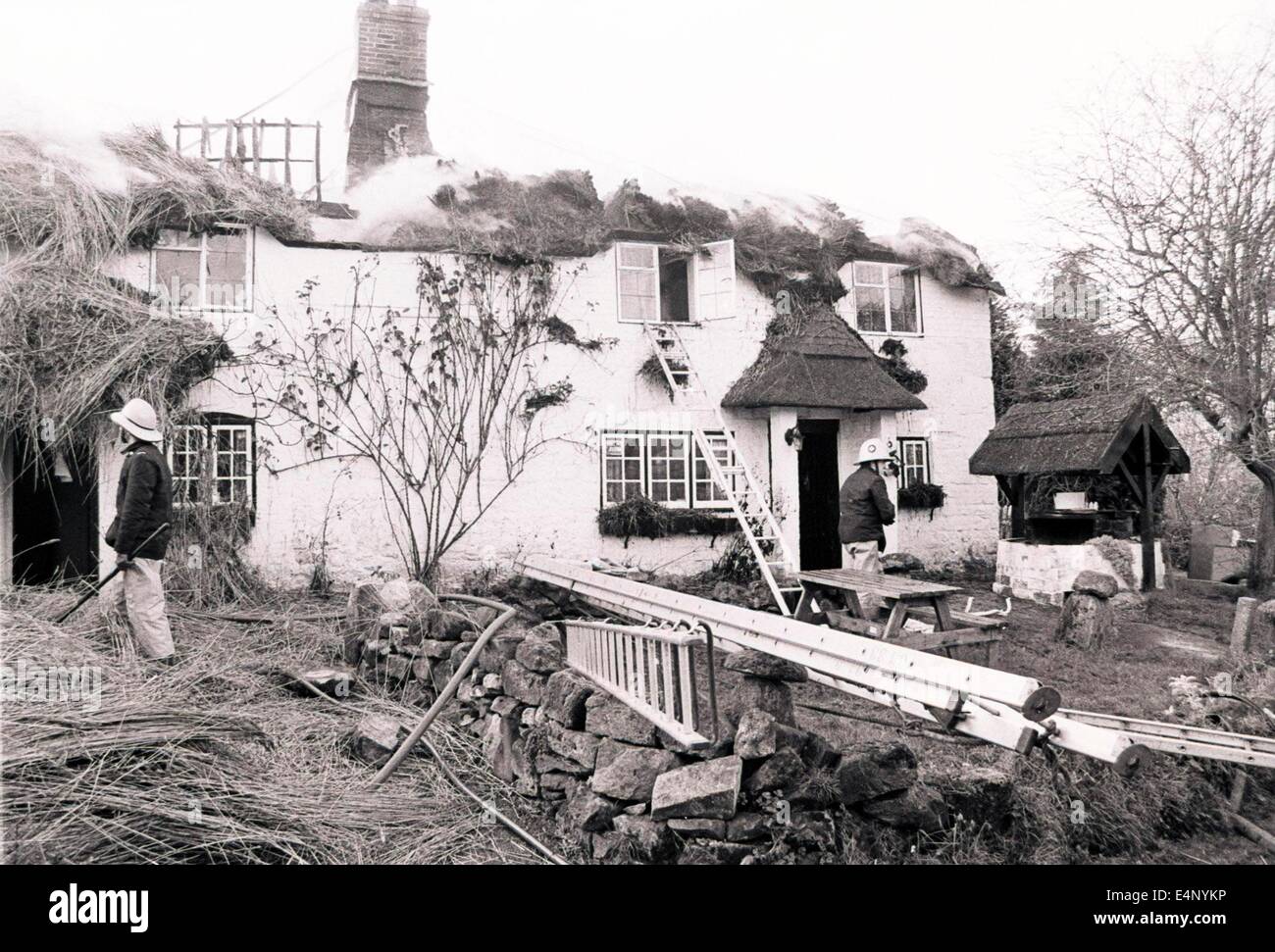 A quaint English thatched cottage destroyed by fire with fire crew ...