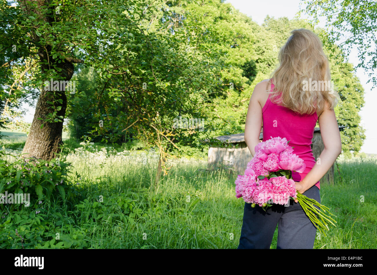 blonde woman back view peony flower bouquet in hand garden background ...