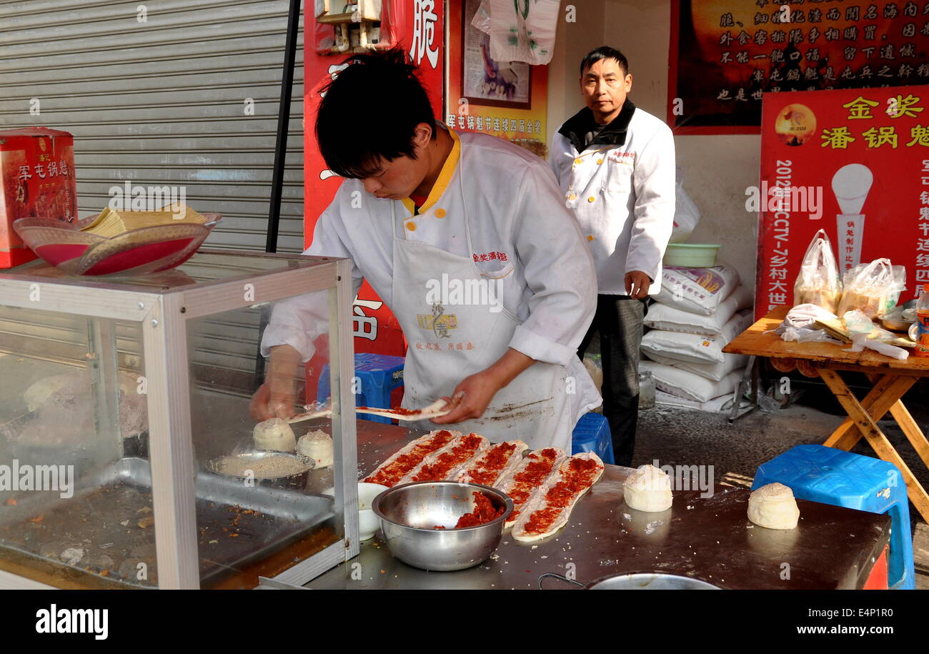 Jun Le, China: Chef spreading spicy pork meat on dough at a roadside ...
