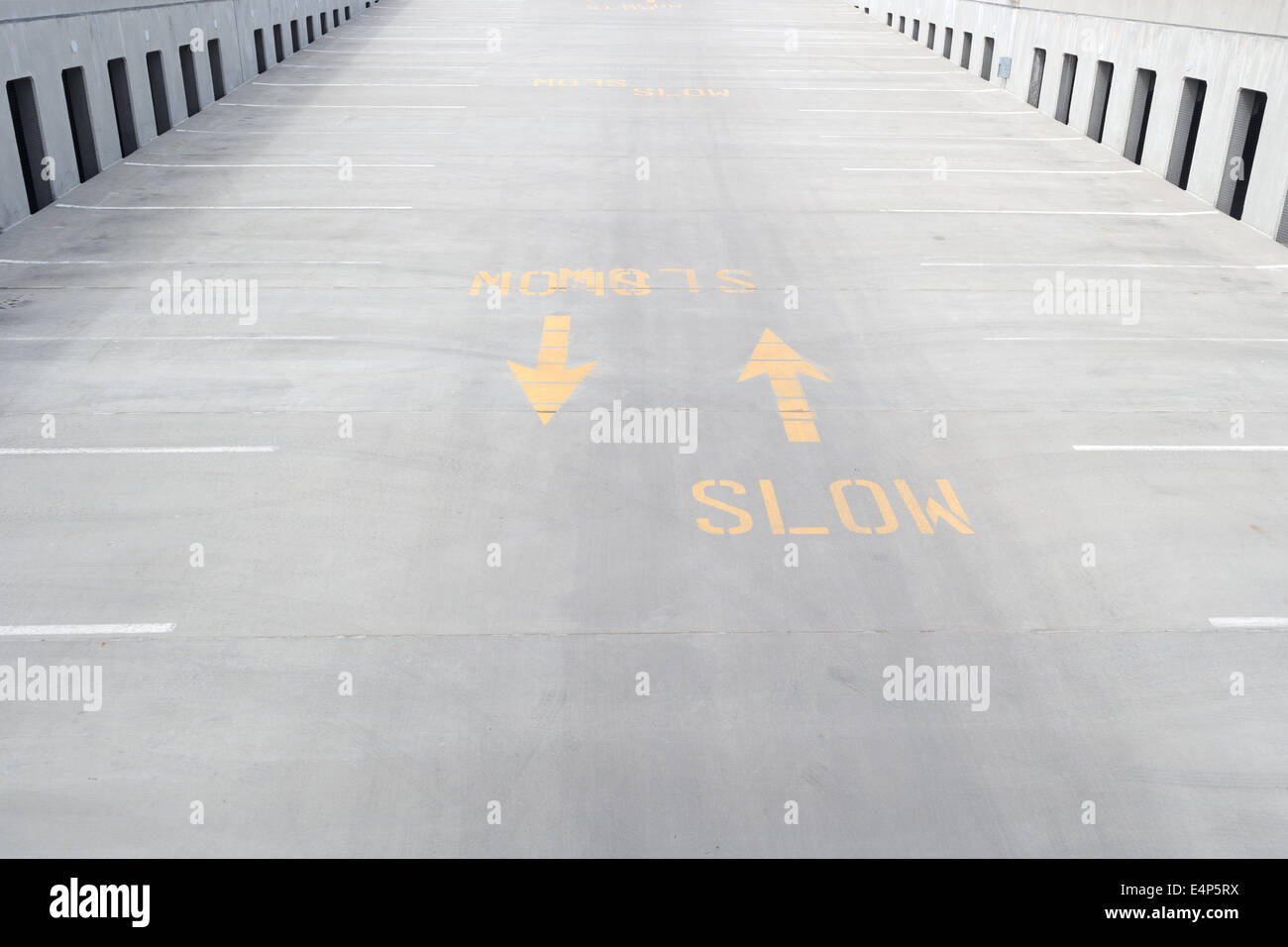 A bright yellow slow sign printed on a concrete exit ramp with arrows ...