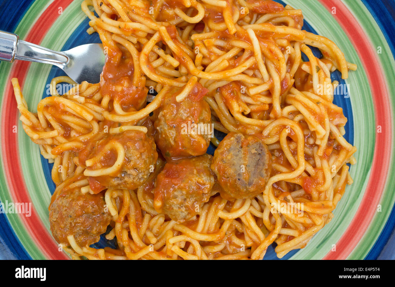 A close view of a hot spaghetti and meatball meal on a colorful plate ...