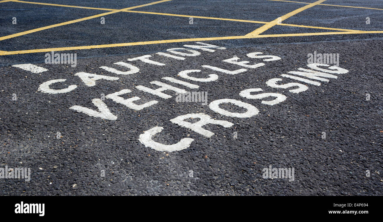 Caution vehicles crossing - painted as warning on tarmac in a quayside ...