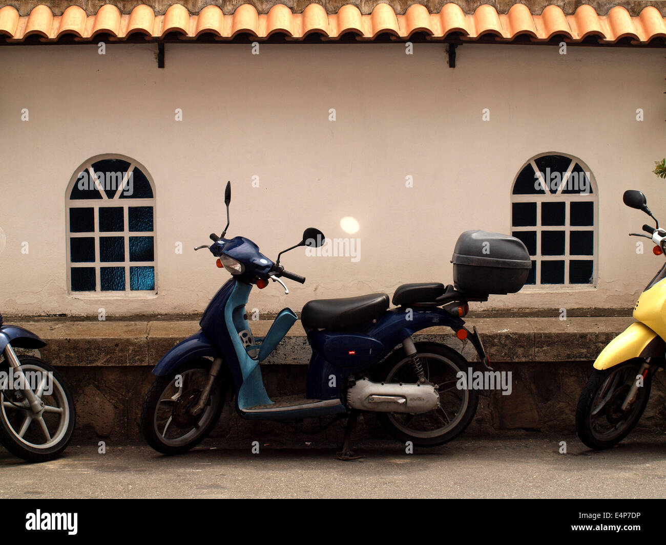 shiny two-tone blue scooter parked outside typical Sicilian building in ...