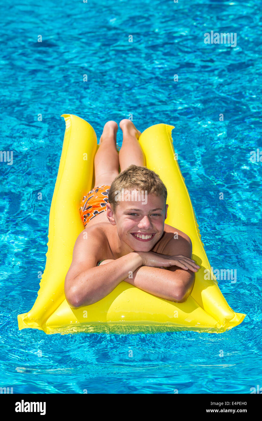 Boy, 12 years, lying on a lilo in a swimming pool Stock Photo: 71794492 ...