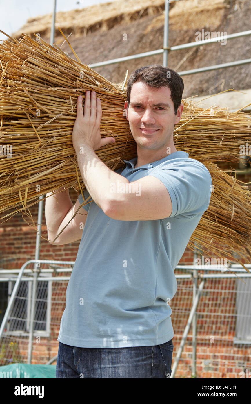 Thatcher Carrying Bundles Of Reeds Working On Roof Stock Photo - Alamy