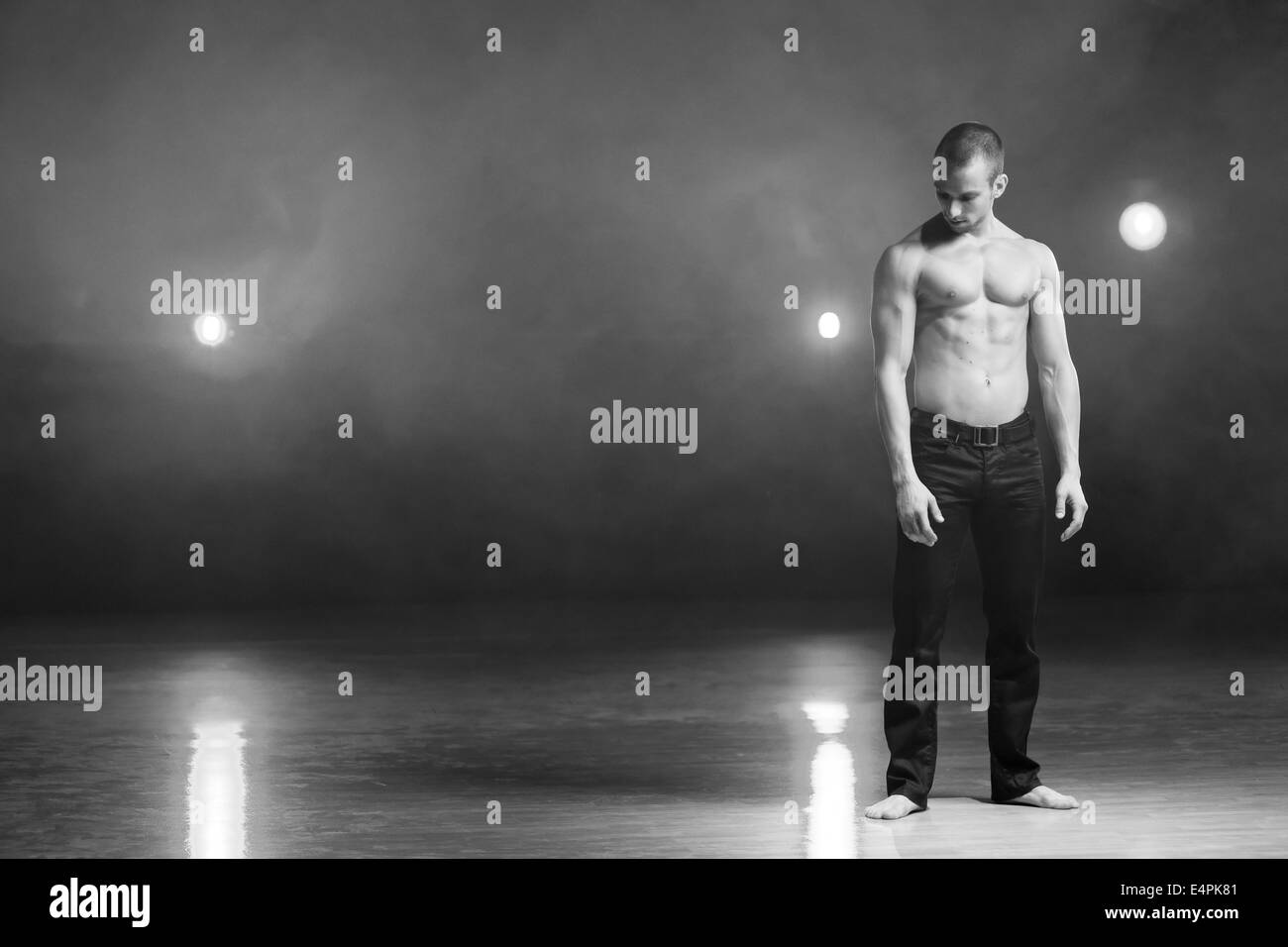 Young and muscular man performing a contemporary dance pose on a stage ...