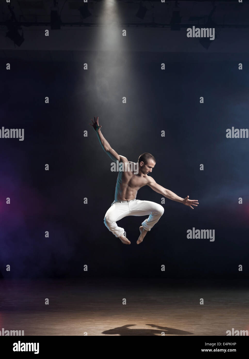 Young and muscular man performing a contemporary dance pose on a stage ...
