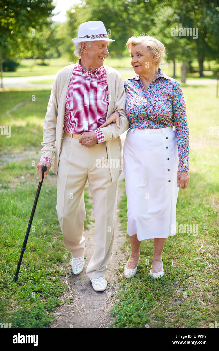 Happy seniors talking while taking a walk in the park Stock Photo - Alamy