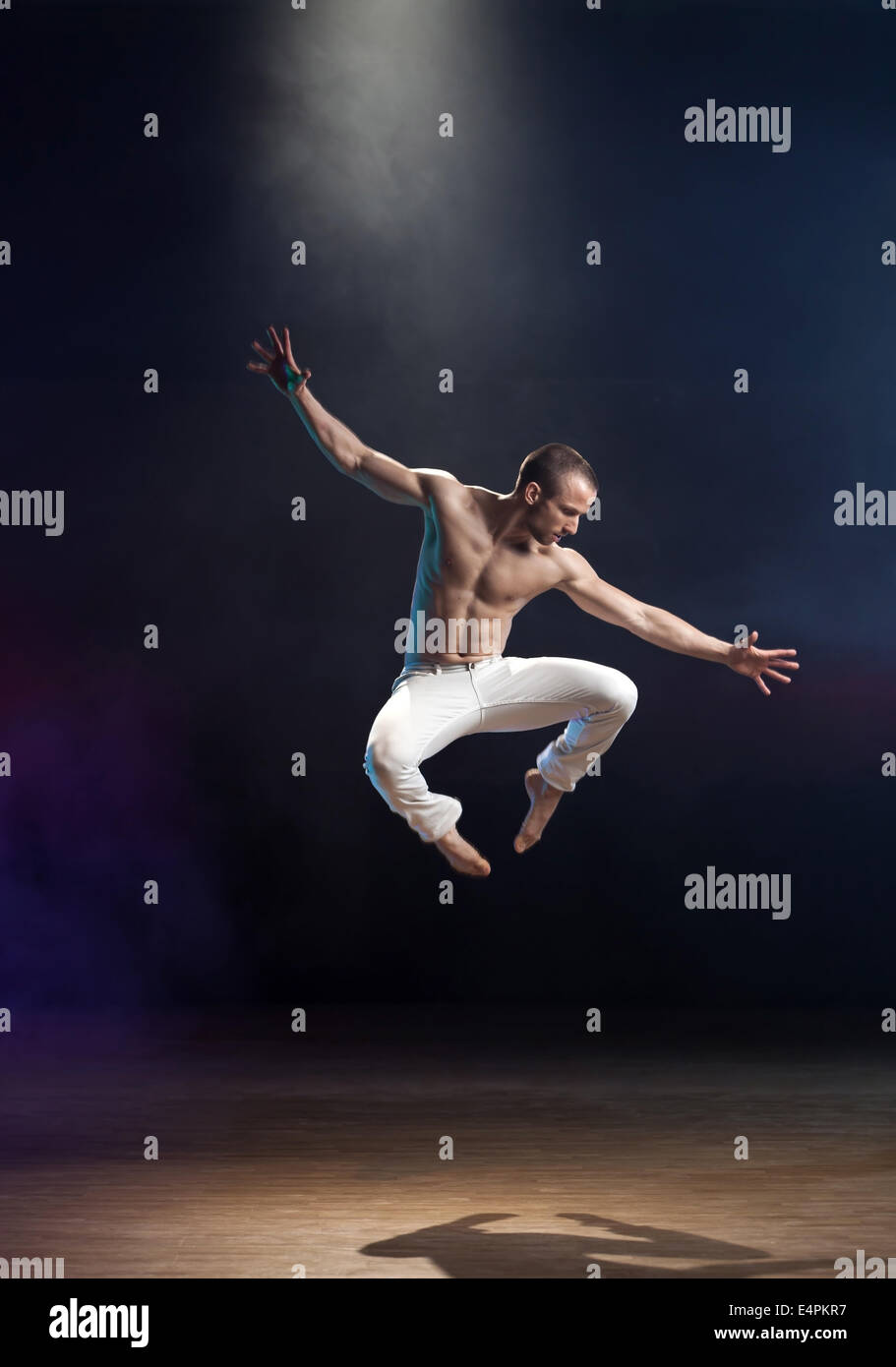 Young and muscular man performing a contemporary dance pose on a stage ...
