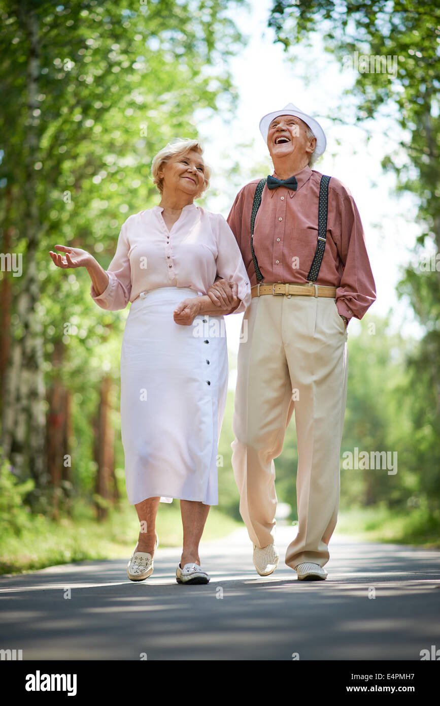 Happy seniors talking and having fun while taking a walk in the park ...