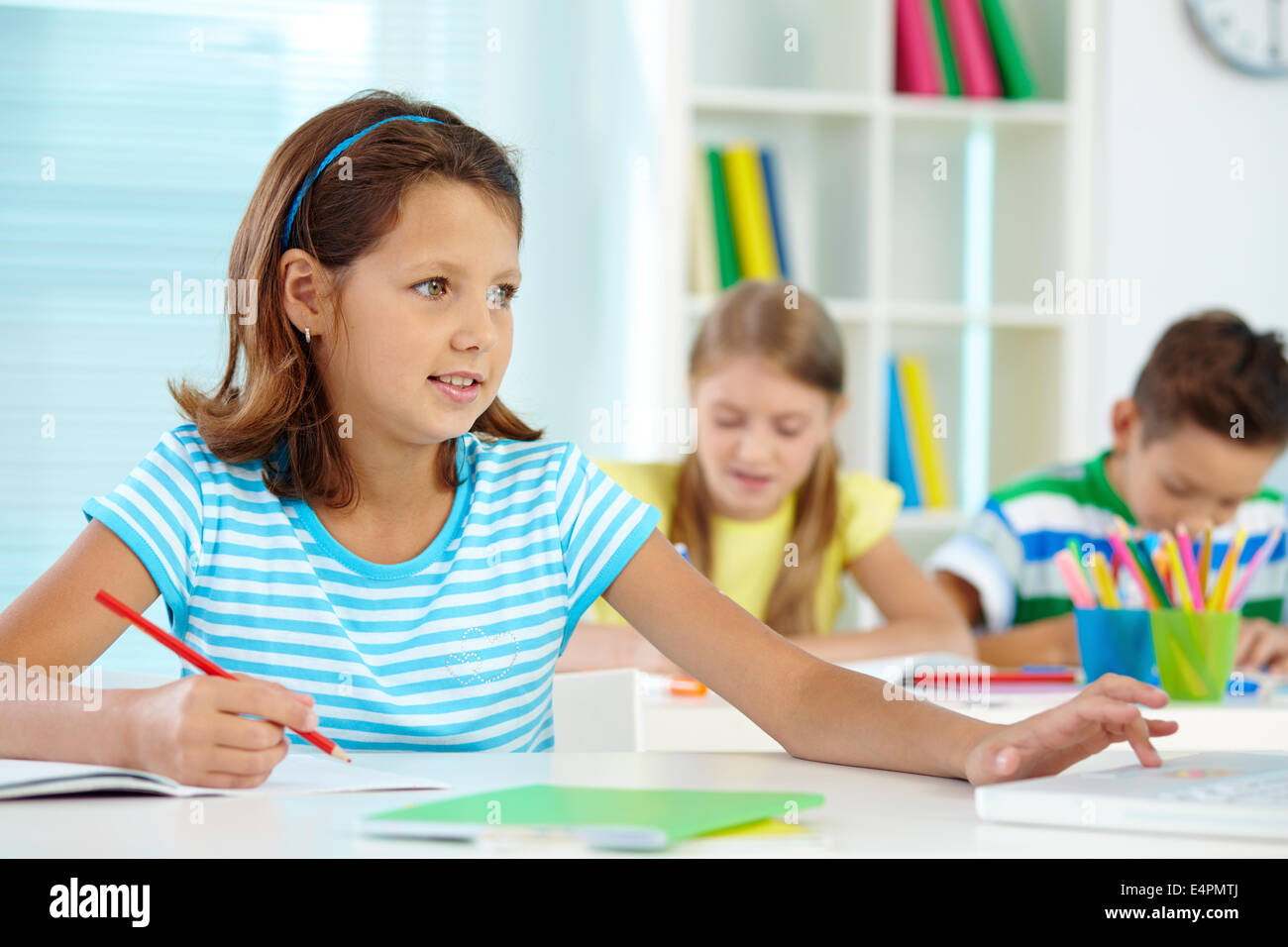 Portrait of cute girl working at workplace with her schoolmates on ...